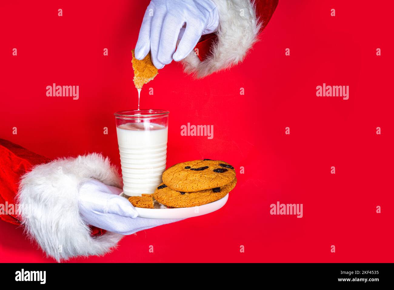 Hand of Santa Claus with traditional Christmas cookie snack with milk ...