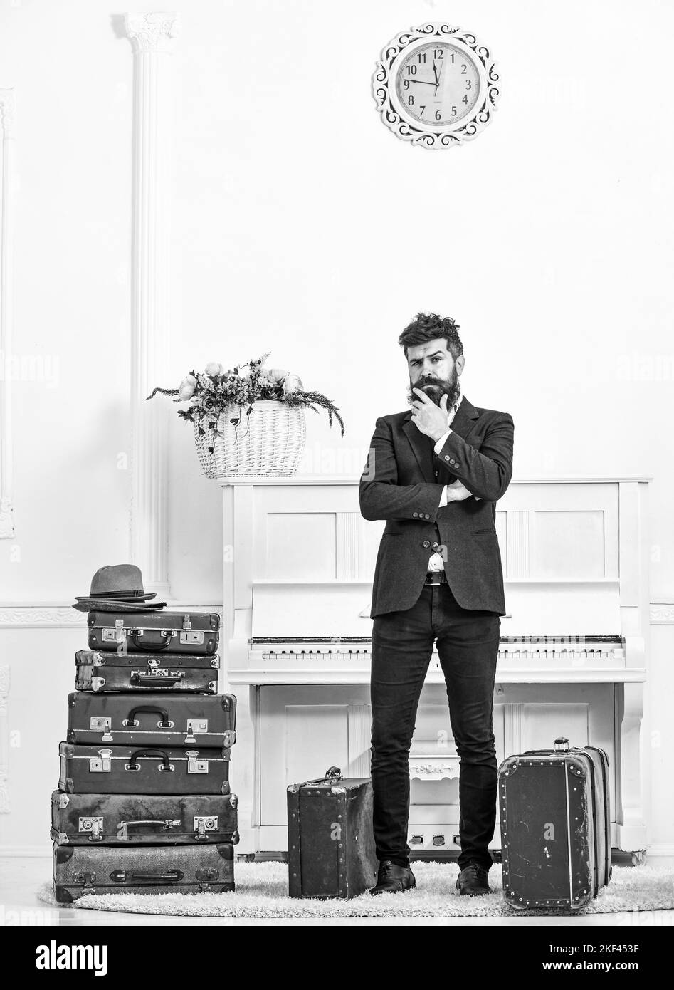 Macho elegant on thoughtful face standing near pile of vintage suitcase ...