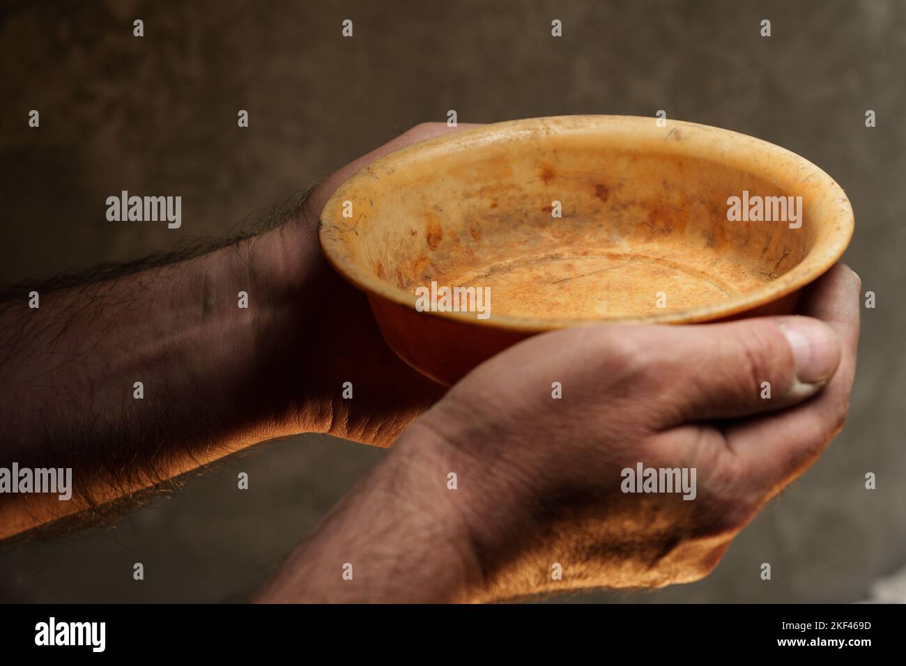 Male hands holding empty plate on dark background, lack of food, hunger ...