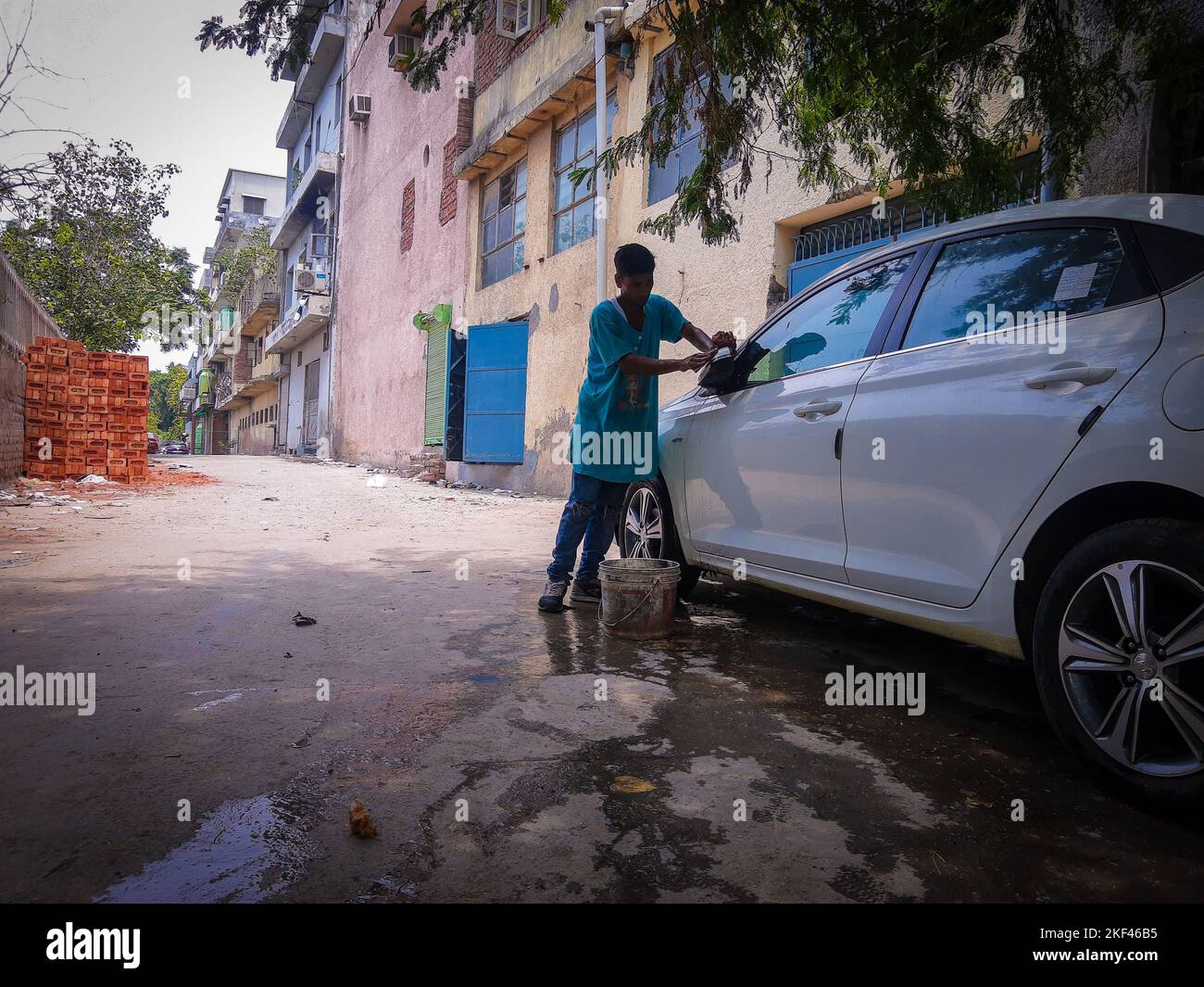 Indian auto mechanic man buffing and polishing car holding polisher in ...