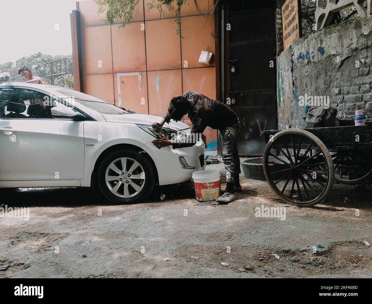 Indian auto mechanic man buffing and polishing car holding polisher in ...