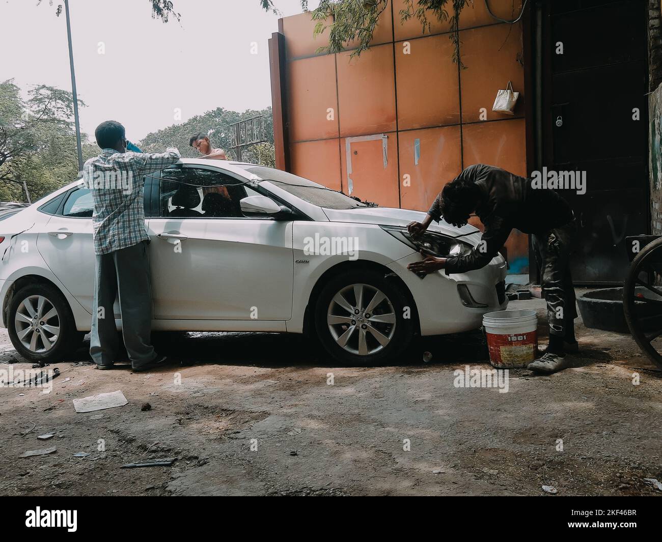 Indian auto mechanic man buffing and polishing car holding polisher in ...