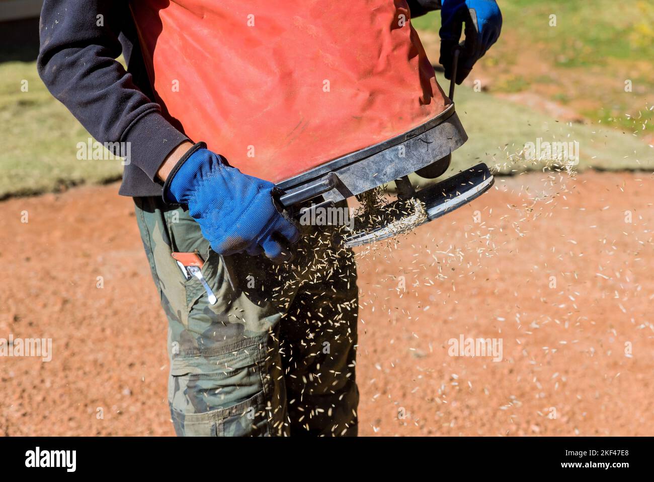 Gardeners landscapers work to sow lawn grass seed using seeding devices ...