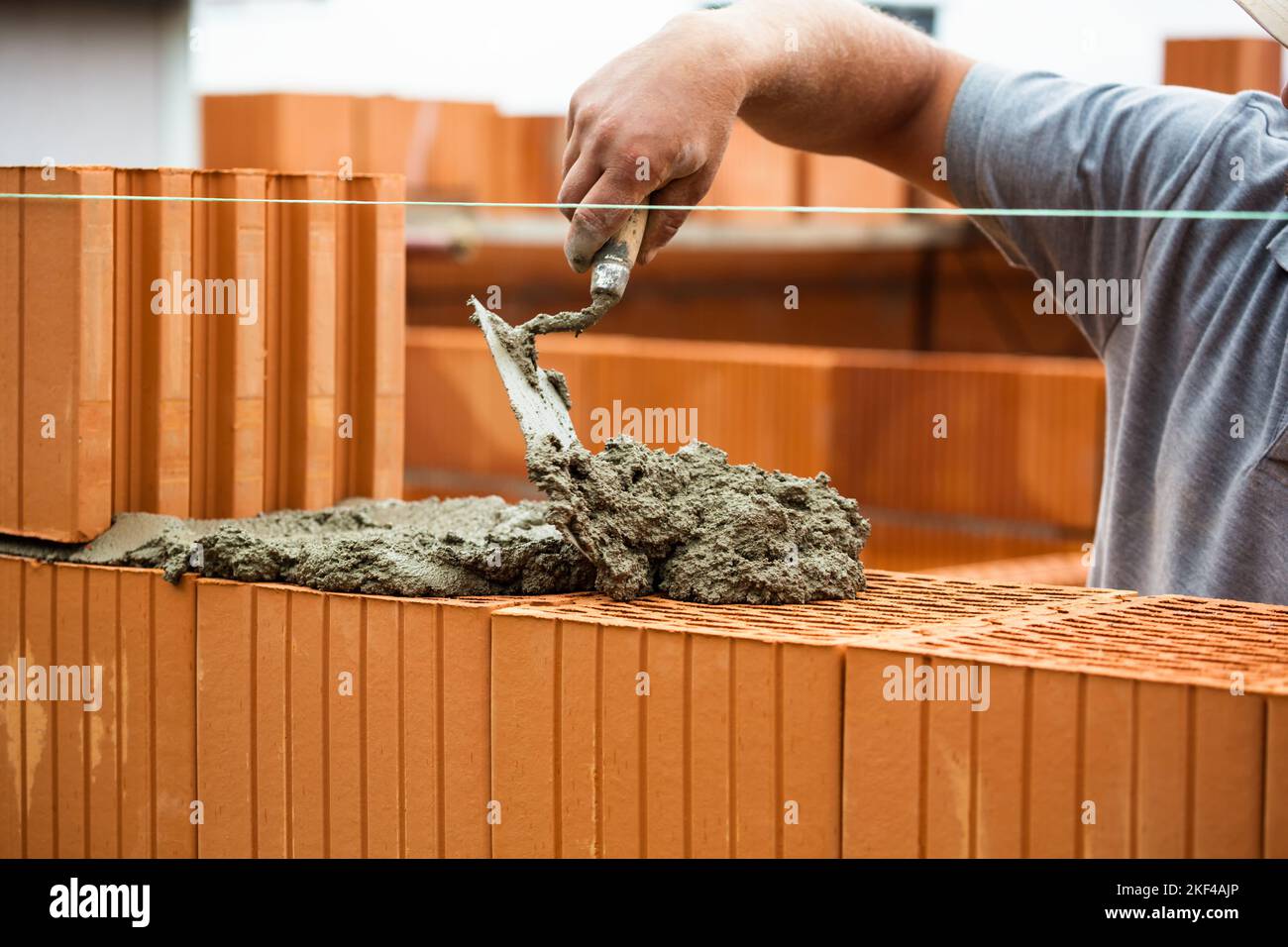 Ein Maurer beim Mauern eines Rohbaus in Massivbauweise. Ziegelmauer ...