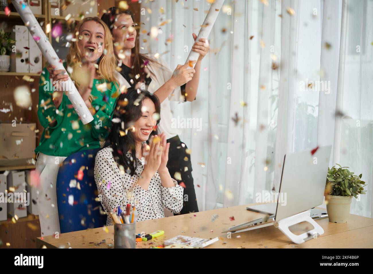 Business colleagues exploding party poppers with sparkling confetti to ...