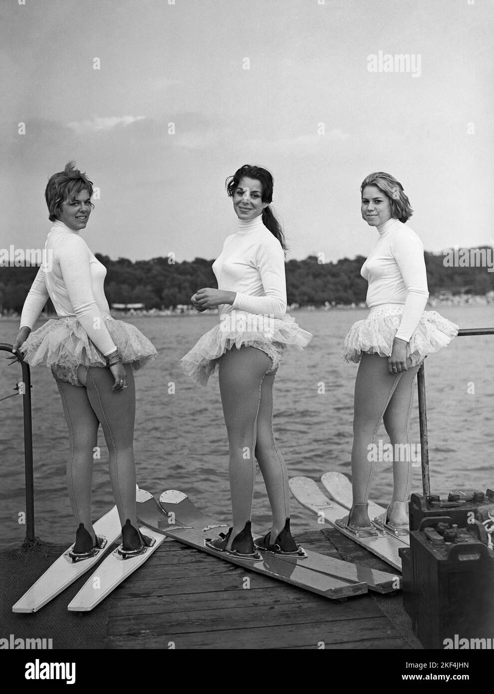 Three girls giving a demonstration of water skiing, left to right ...