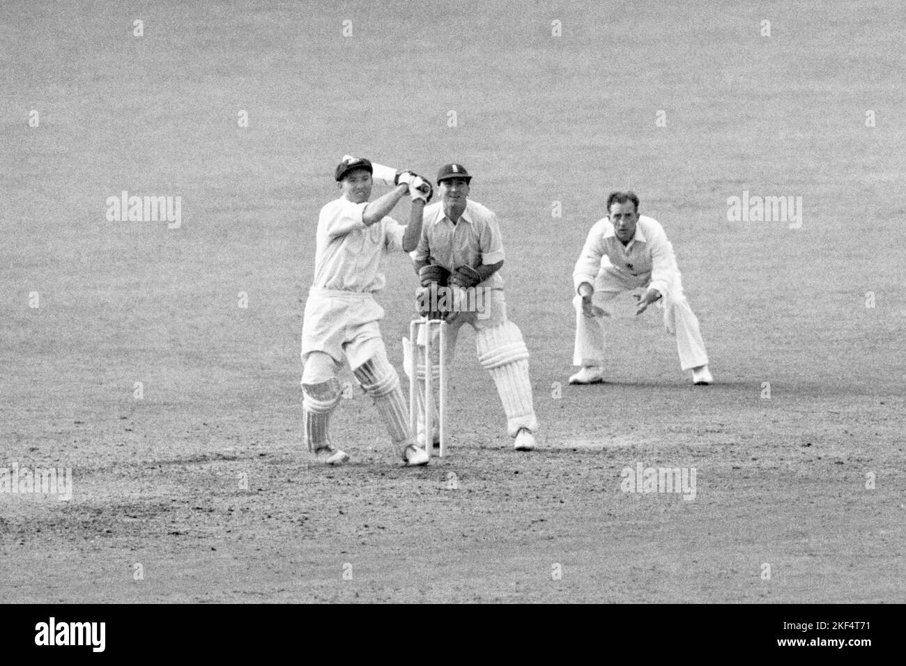 Australia's Ray Lindwall (r) smashes the ball to the boundary, watched ...