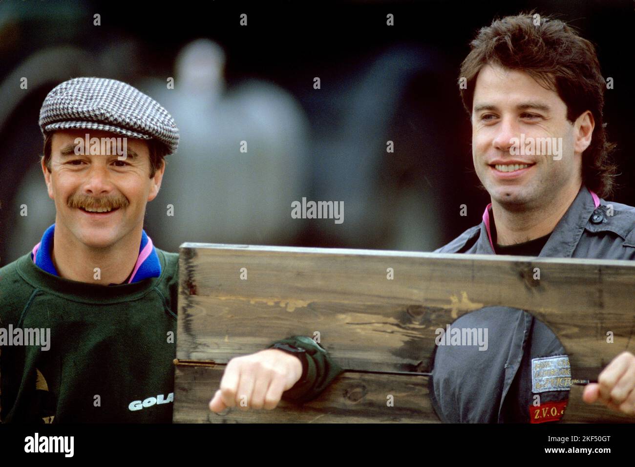 (L-R) Nigel Mansell and John Travolta pose in the stocks to publicize ...