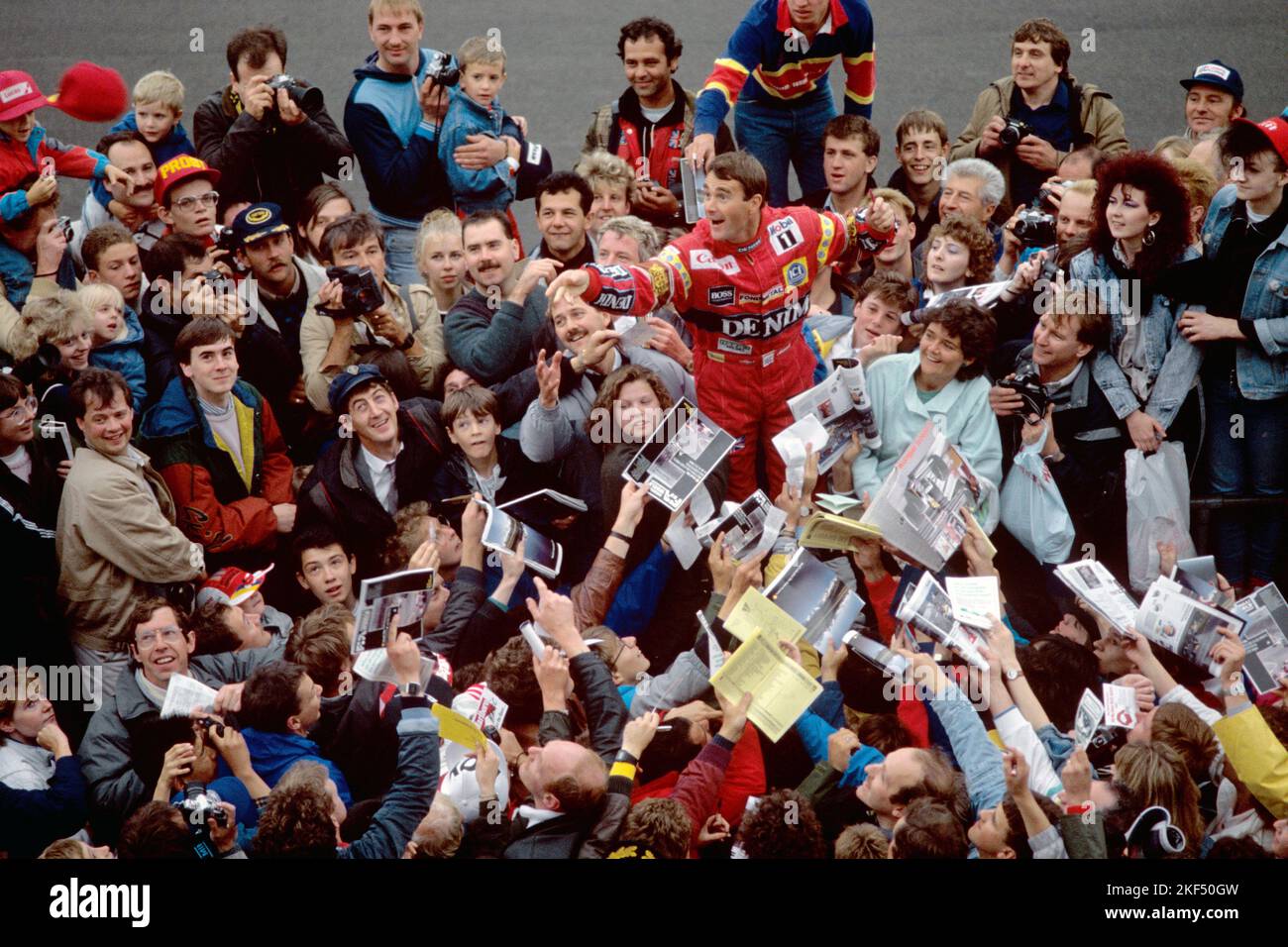Nigel Mansell throws his cap into a throng of fans after finishing ...