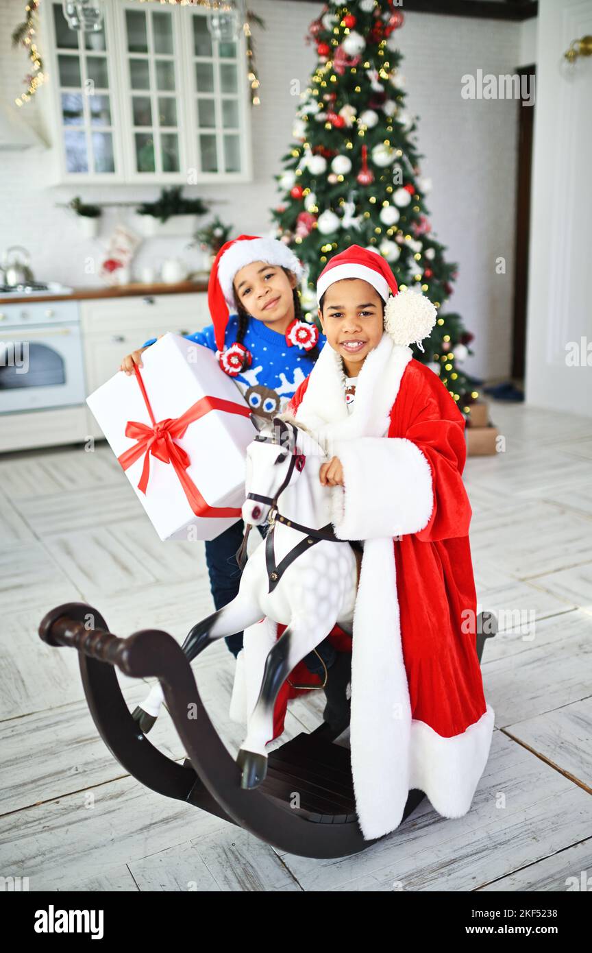 a brother and sister in a Santa costume and a sweater with a deer, ride ...