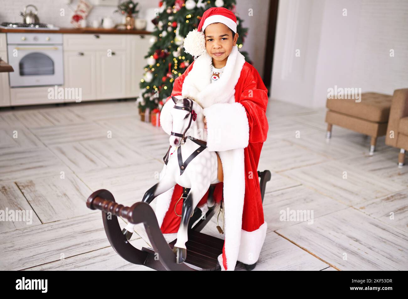 african american boy in a red santa costume smiles while sitting on a ...