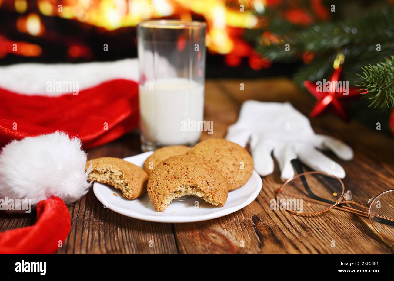 bitten oatmeal cookie and an unfinished glass of milk on a wooden table ...
