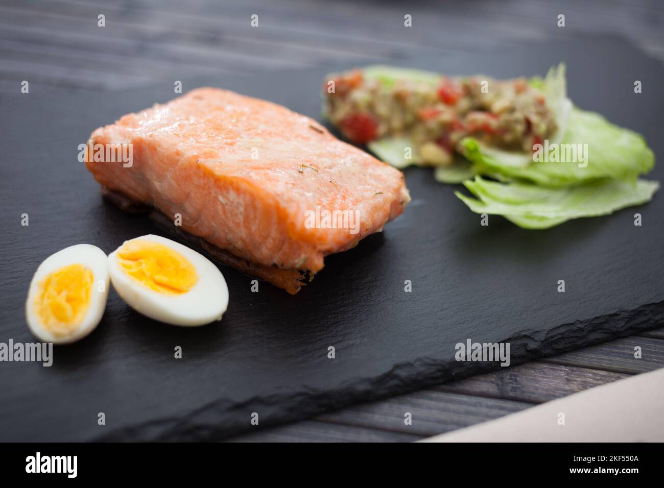 baked salmon fillet with homemade guacamole and quail eggs halves Stock ...