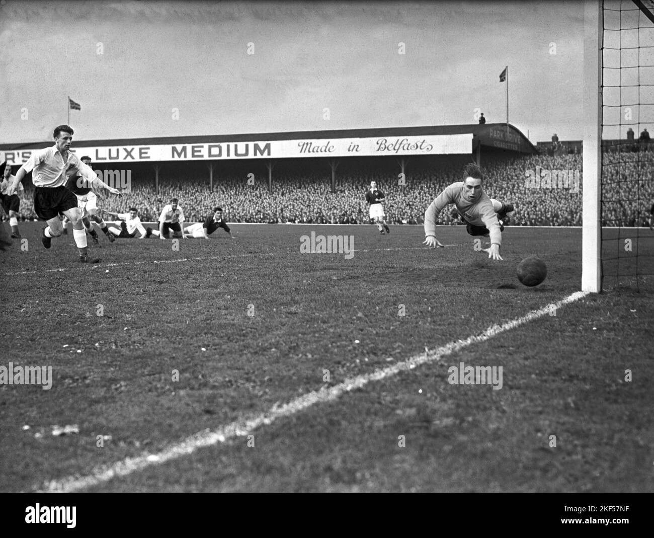 England's Roger Byrne (l) watches as goalkeeper Ray Wood (r) dives for ...