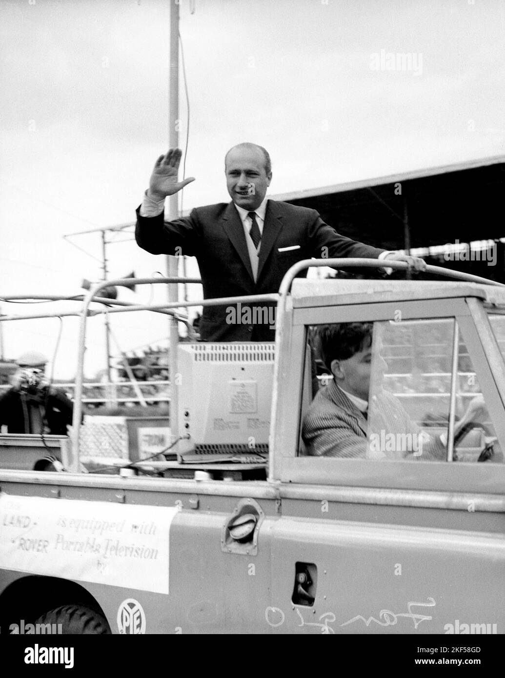 Juan Manuel Fangio waves to the crowds at Silverstone on a parade lap ...