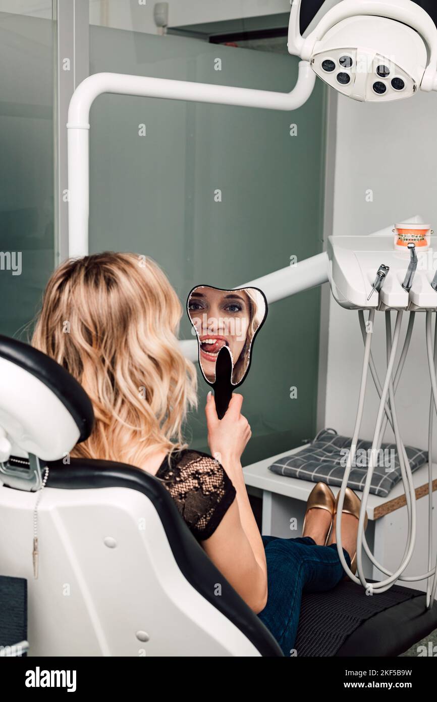 A woman in a dental chair looks in the mirror at her teeth Stock Photo ...