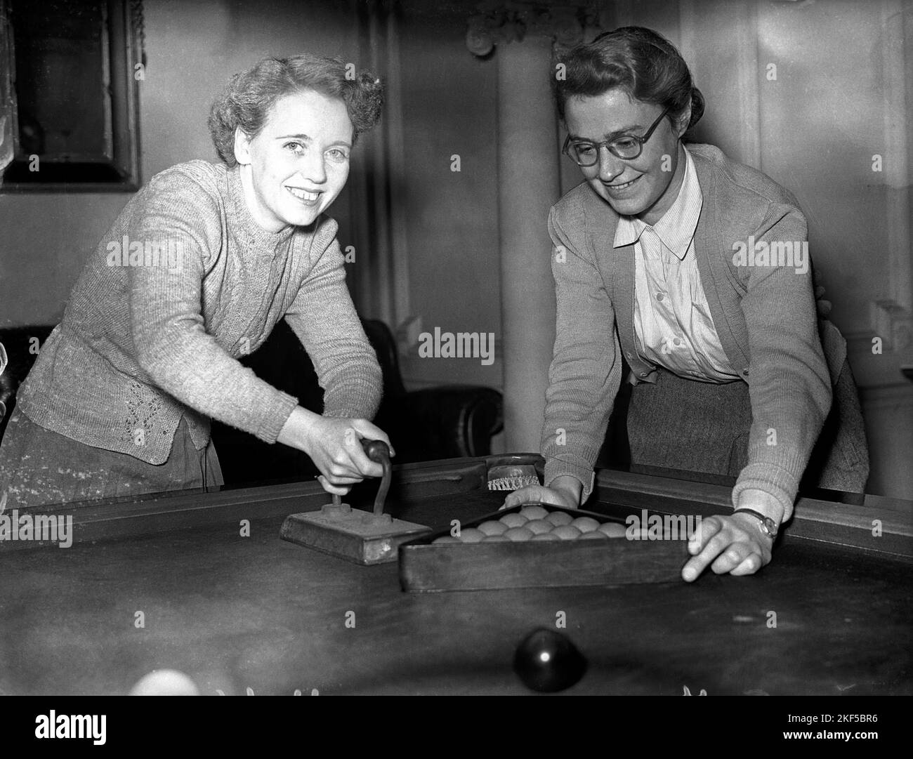 (L-R) Ms Pat Holden gives the baize a quick iron as Miss Clara Cottem ...