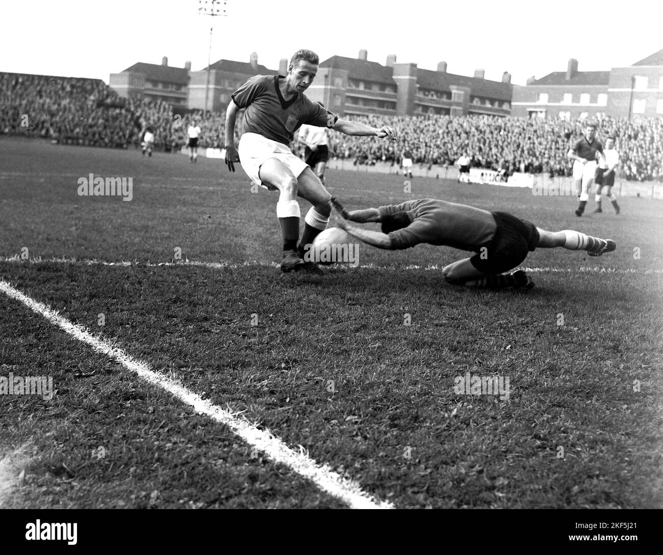 Queens Park Rangers goalkeeper Ron Springett (r) dives at the feet of ...
