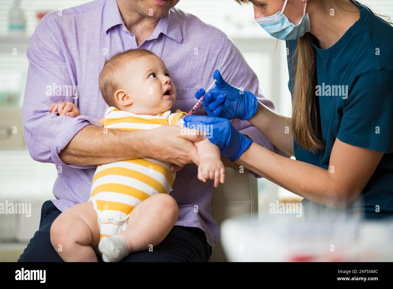 Female nurse with surgical mask and in gloves giving vaccine injection ...