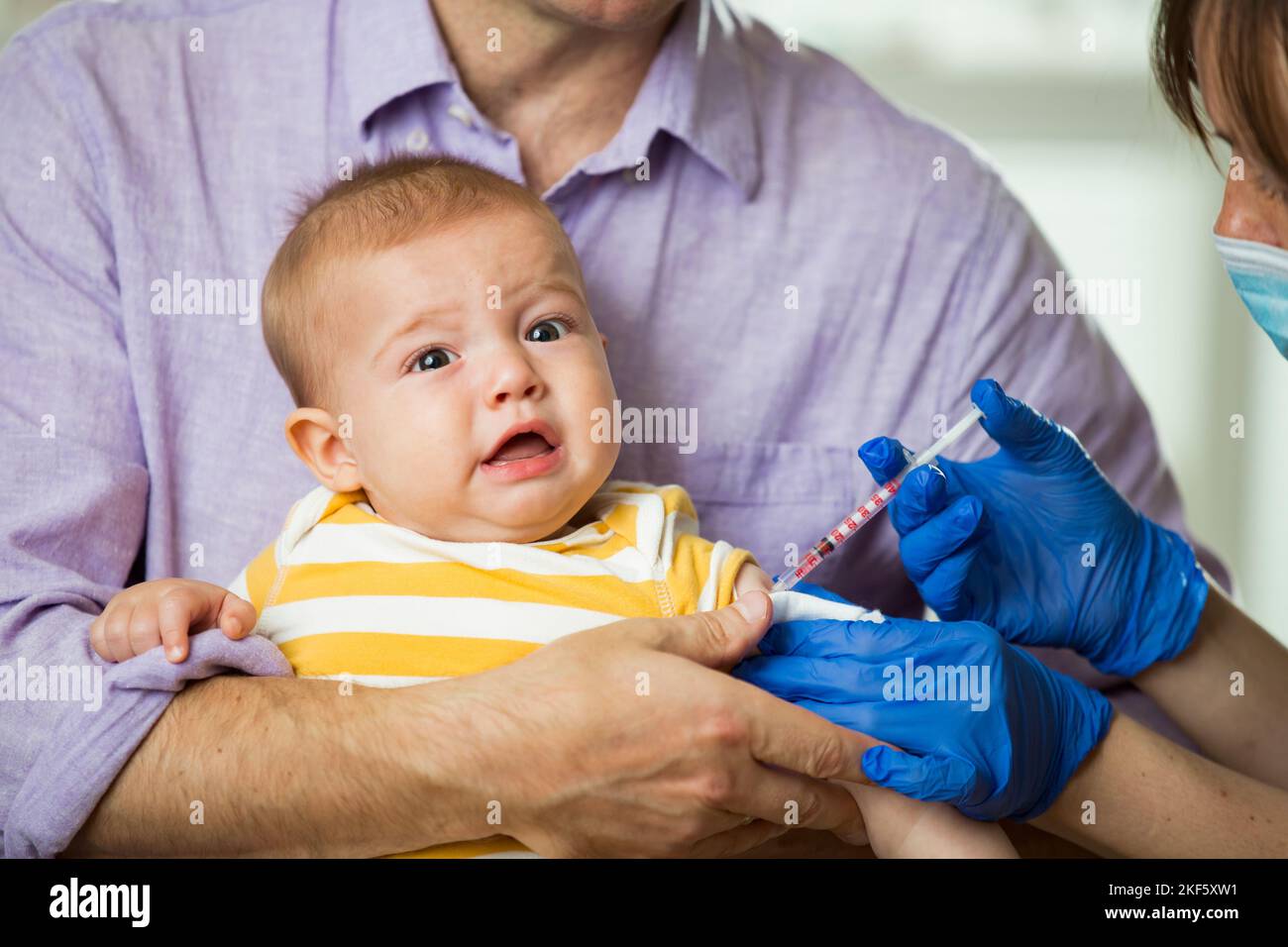 Female nurse with surgical mask and in gloves giving vaccine injection ...
