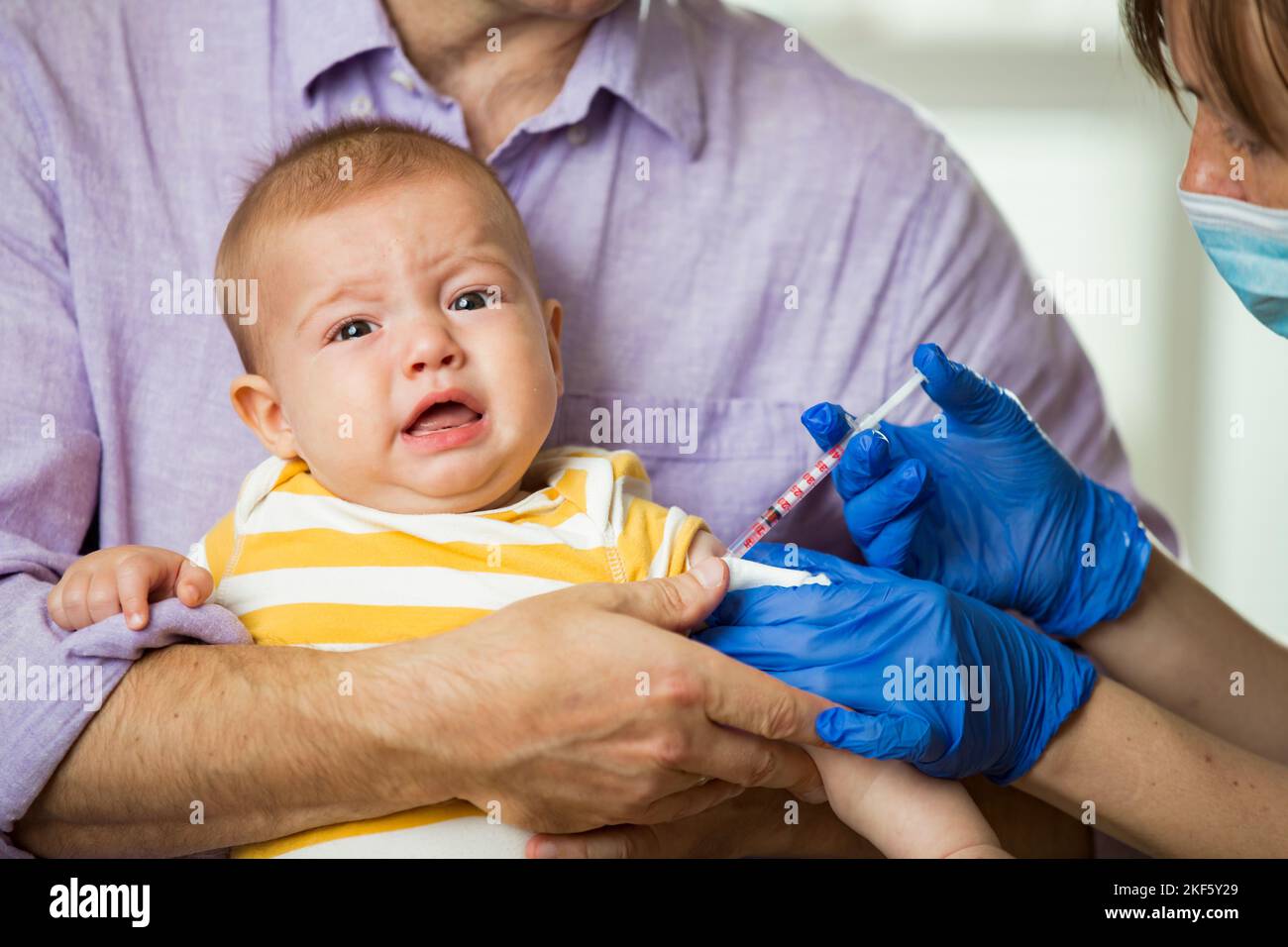 Female nurse with surgical mask and in gloves giving vaccine injection ...
