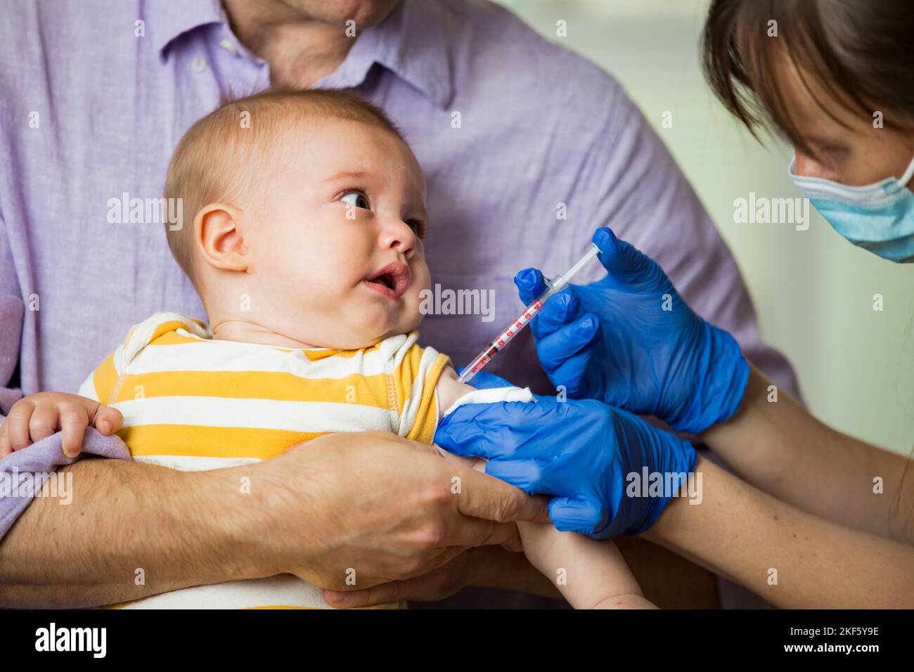 Female nurse with surgical mask and in gloves giving vaccine injection ...