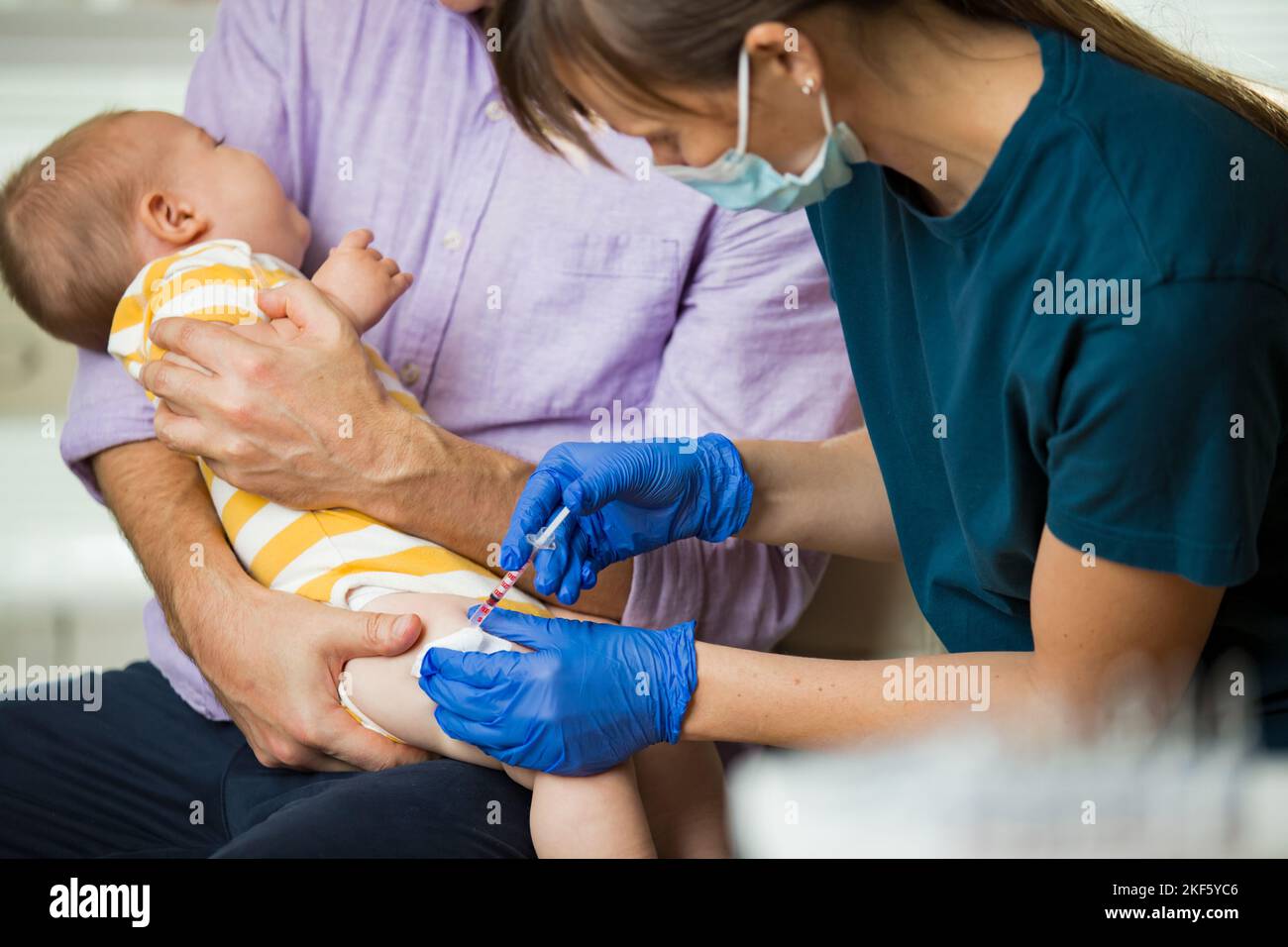 Female nurse with surgical mask and in gloves giving vaccine injection ...