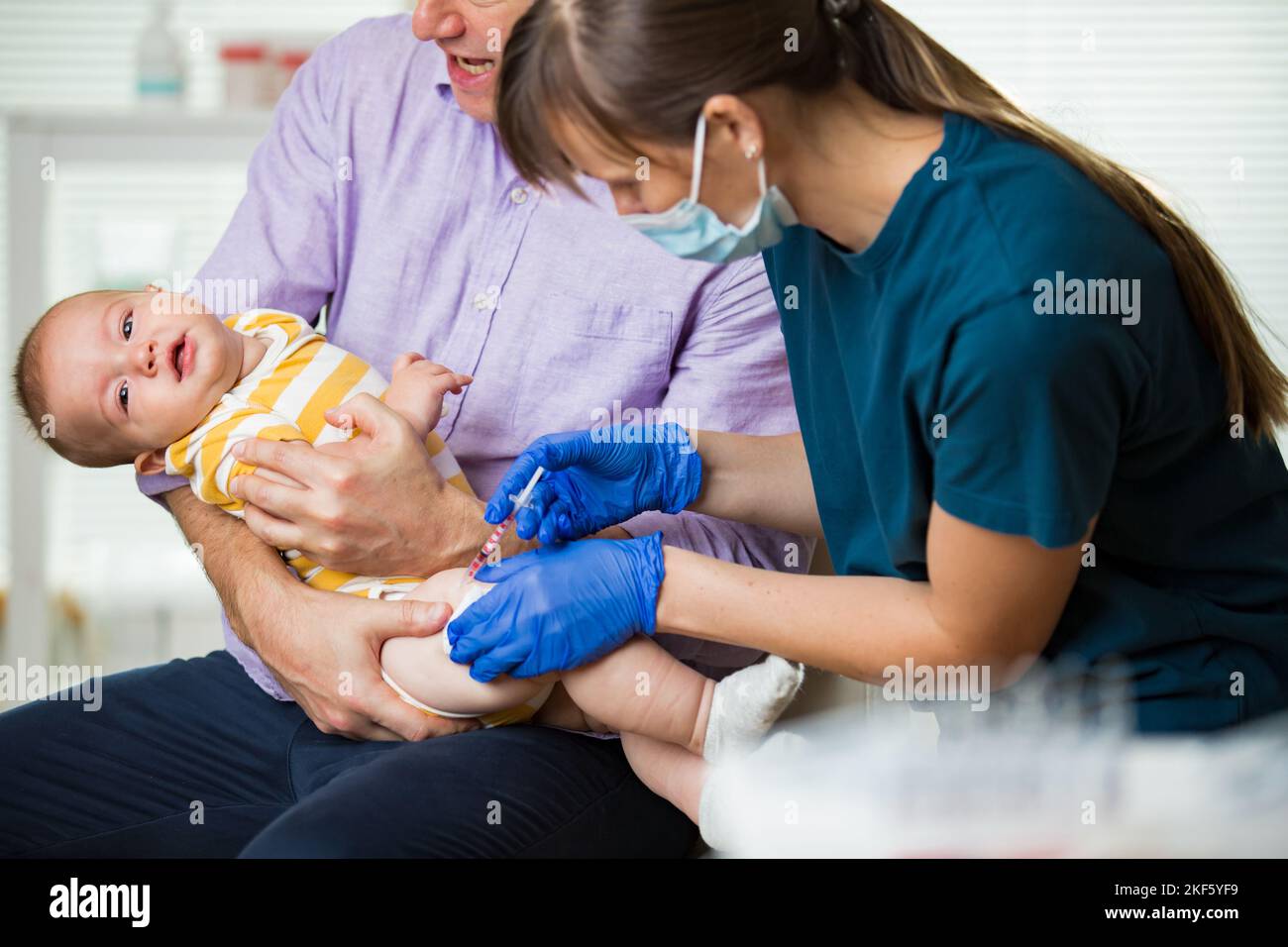 Female nurse with surgical mask and in gloves giving vaccine injection ...
