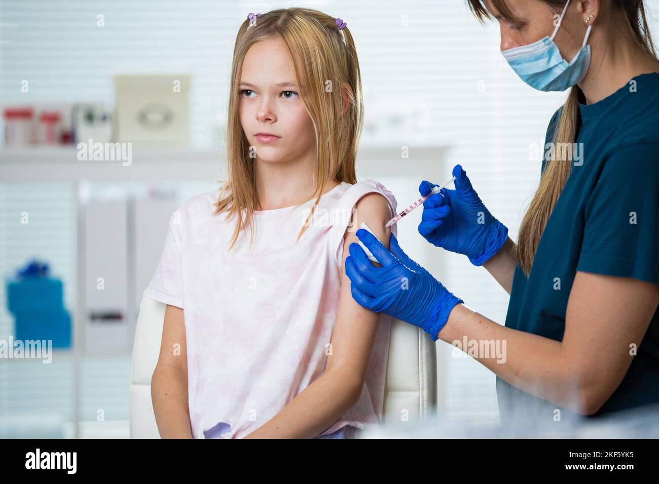 Female nurse with surgical mask and in gloves giving vaccine injection ...