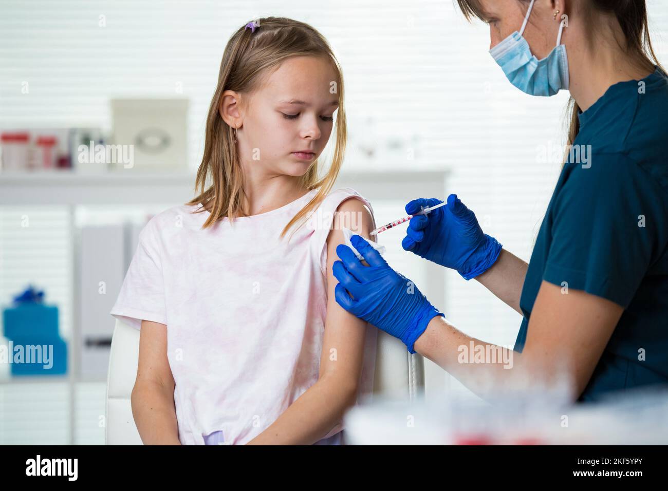 Female nurse with surgical mask and in gloves giving vaccine injection ...