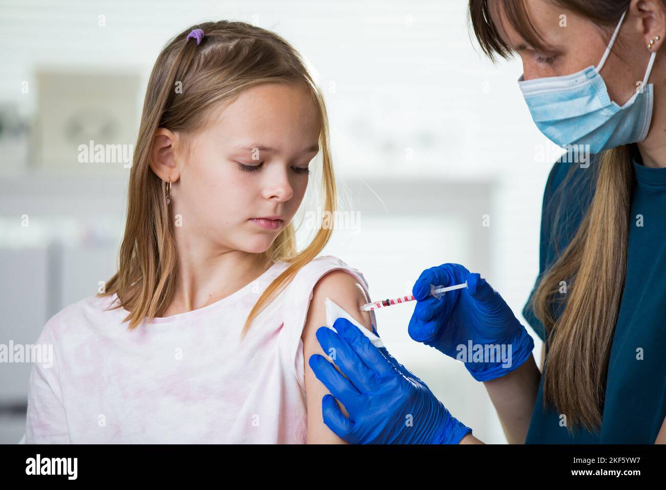 Female nurse with surgical mask and in gloves giving vaccine injection ...