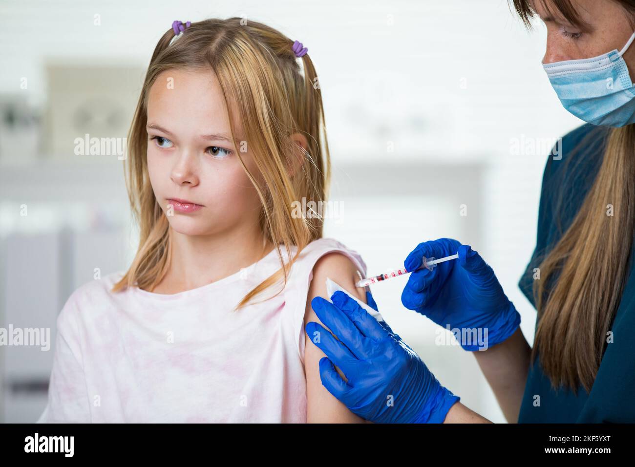 Female nurse with surgical mask and in gloves giving vaccine injection ...