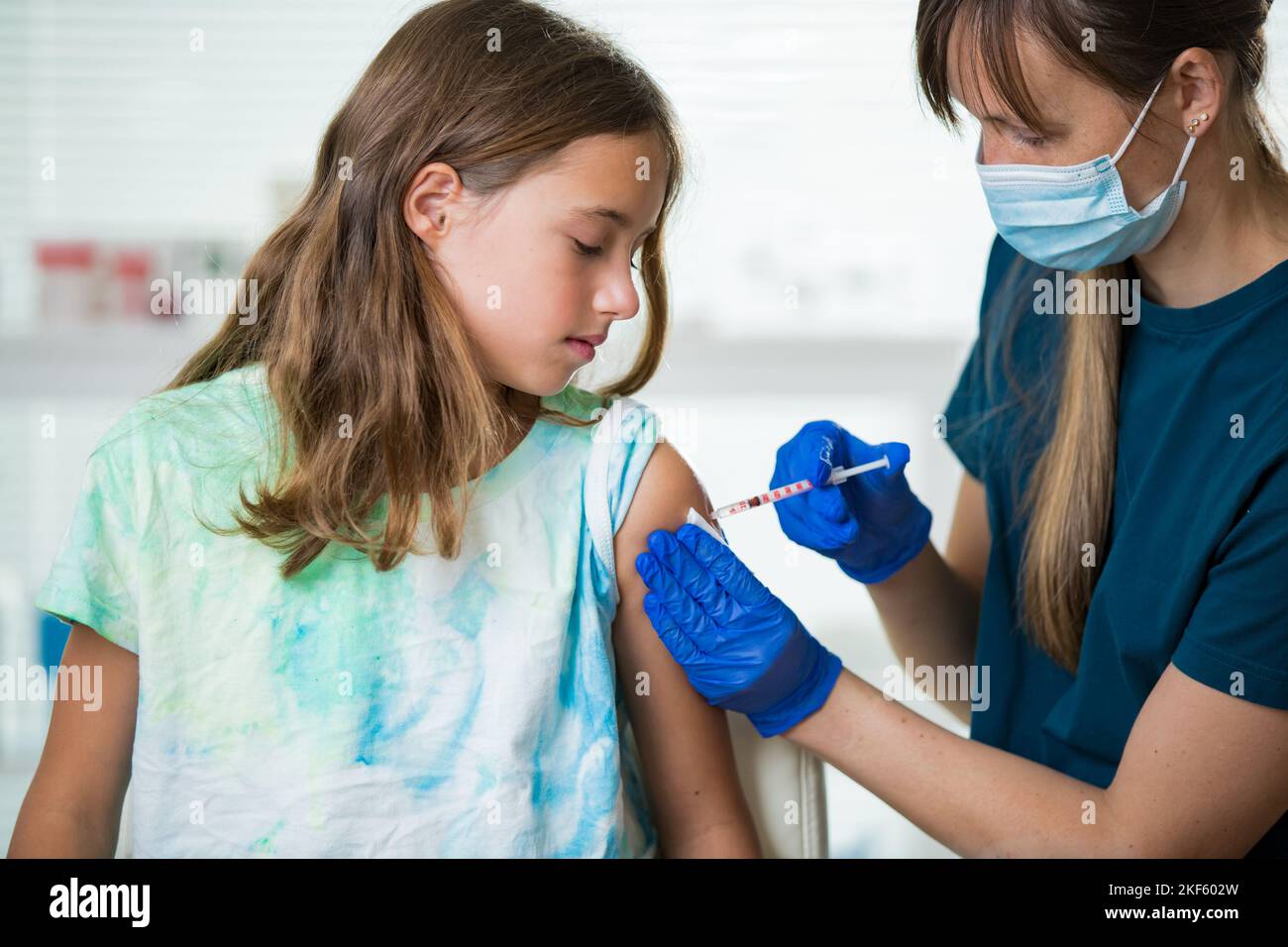 Female nurse with surgical mask and in gloves giving vaccine injection ...