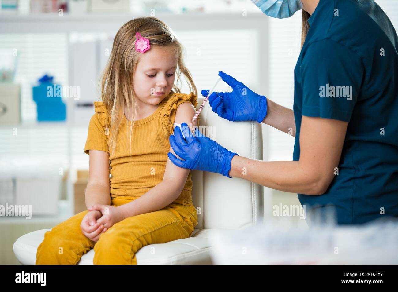 Female nurse with surgical mask and in gloves giving vaccine injection ...