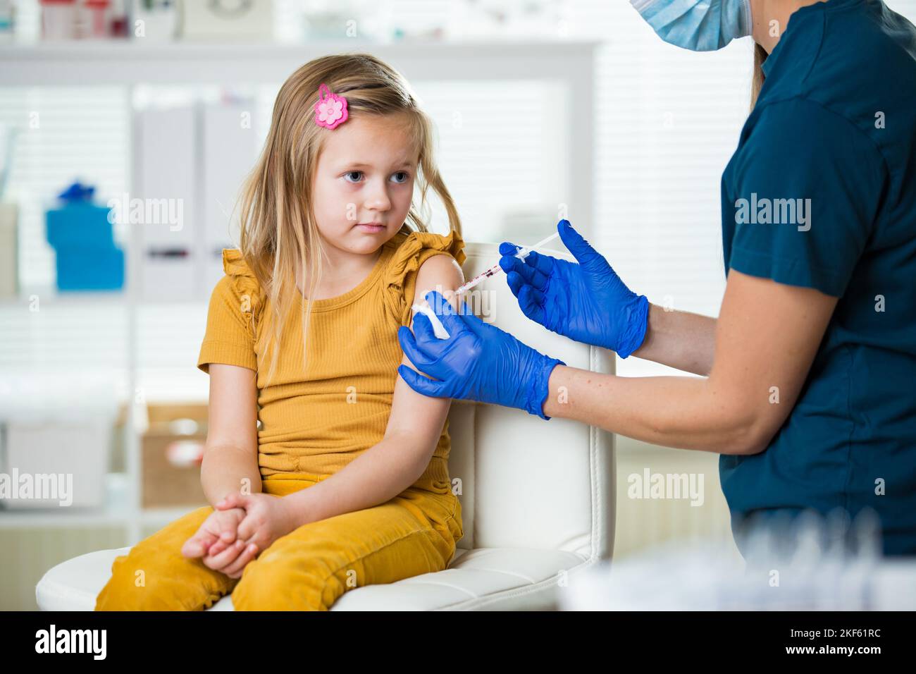 Female nurse with surgical mask and in gloves giving vaccine injection ...