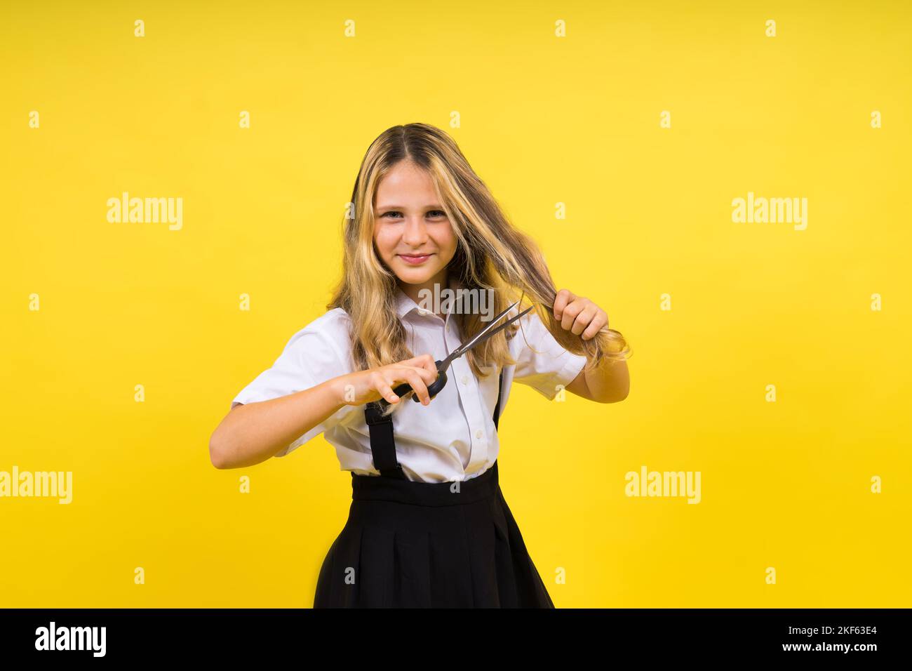 Teenage school girl with scissors, isolated on yellow background. Child ...