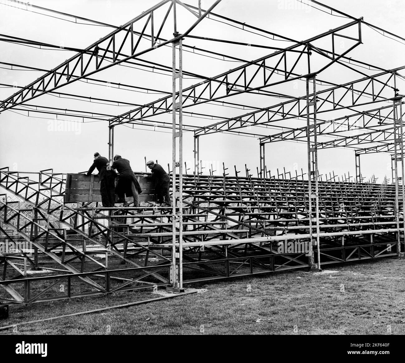 Wooden seating being put into position on the partly erected grandstand ...