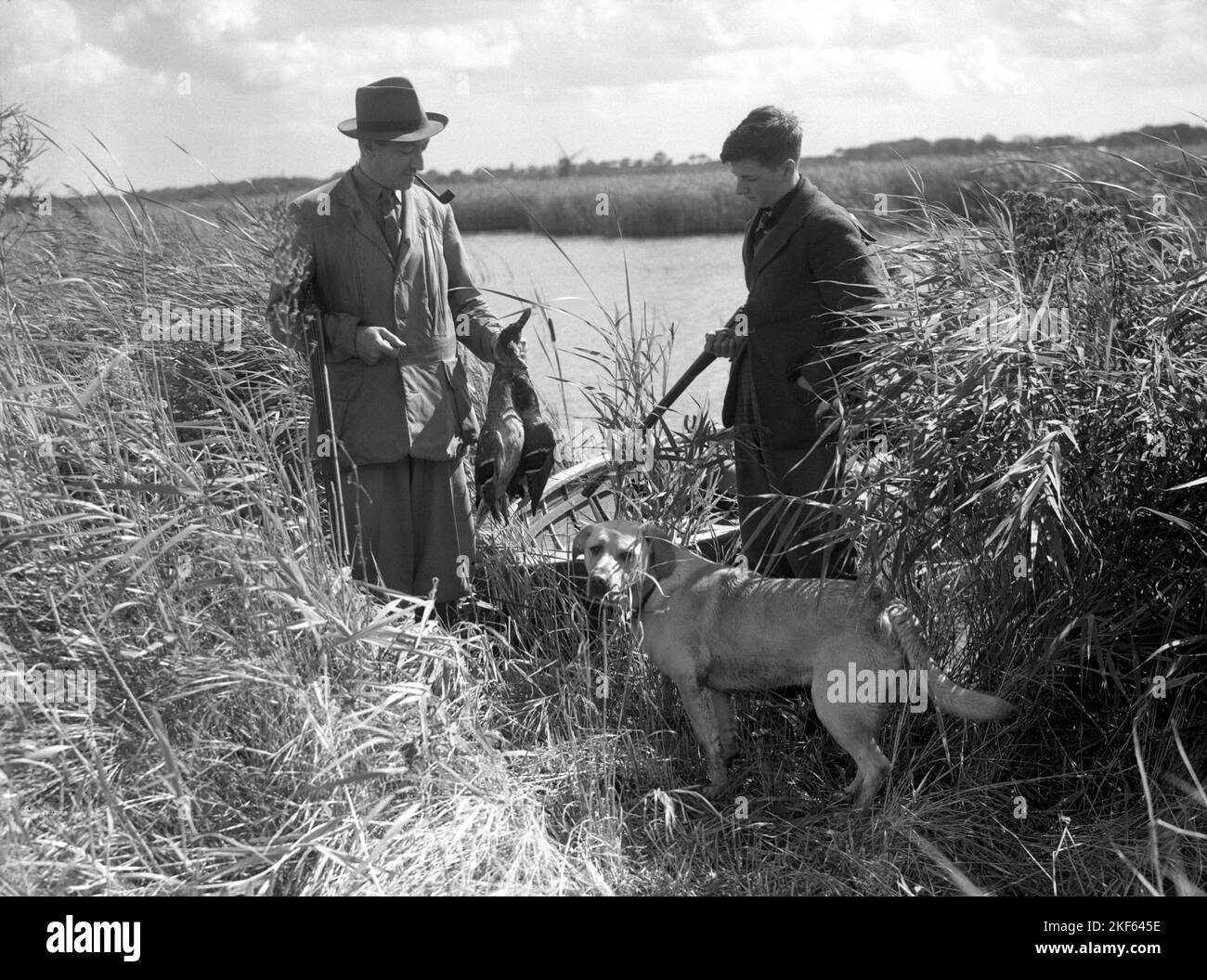 Edward Marsh and his retriever "Bounce" shows his son Anthony how to ...