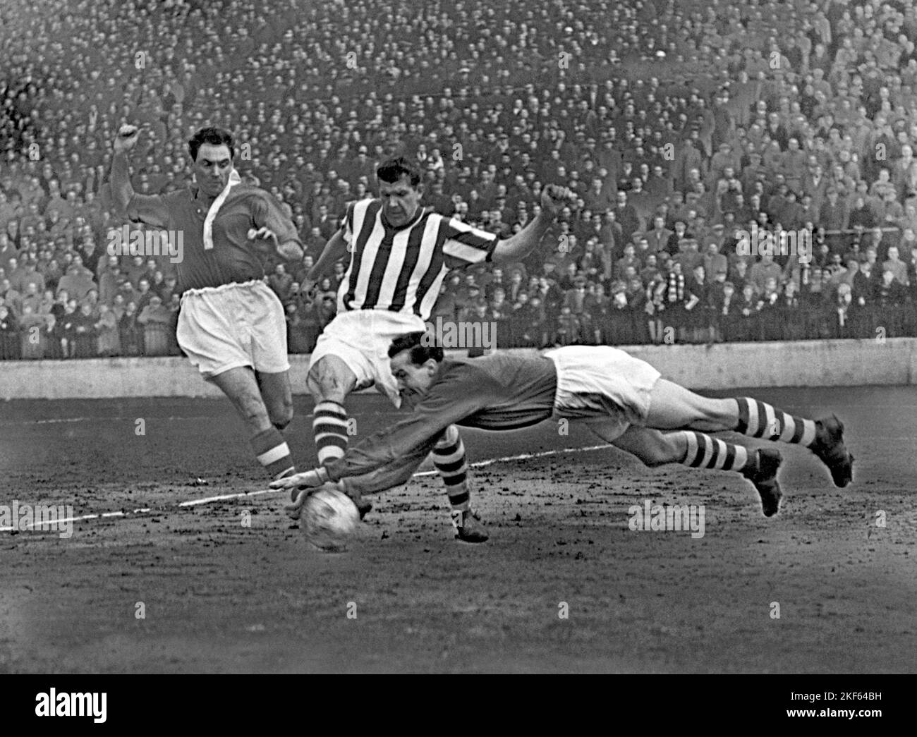 Neil Kennon, the Huddersfield goalkeeper, goes down to the feet of ...