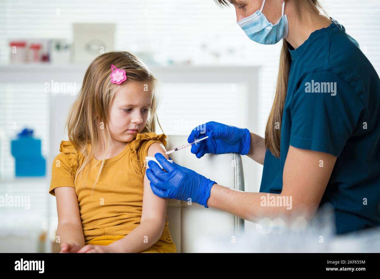 Female nurse with surgical mask and in gloves giving vaccine injection ...