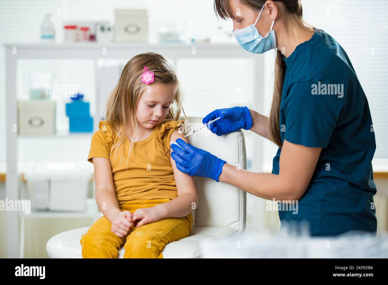 Female nurse with surgical mask and in gloves giving vaccine injection ...