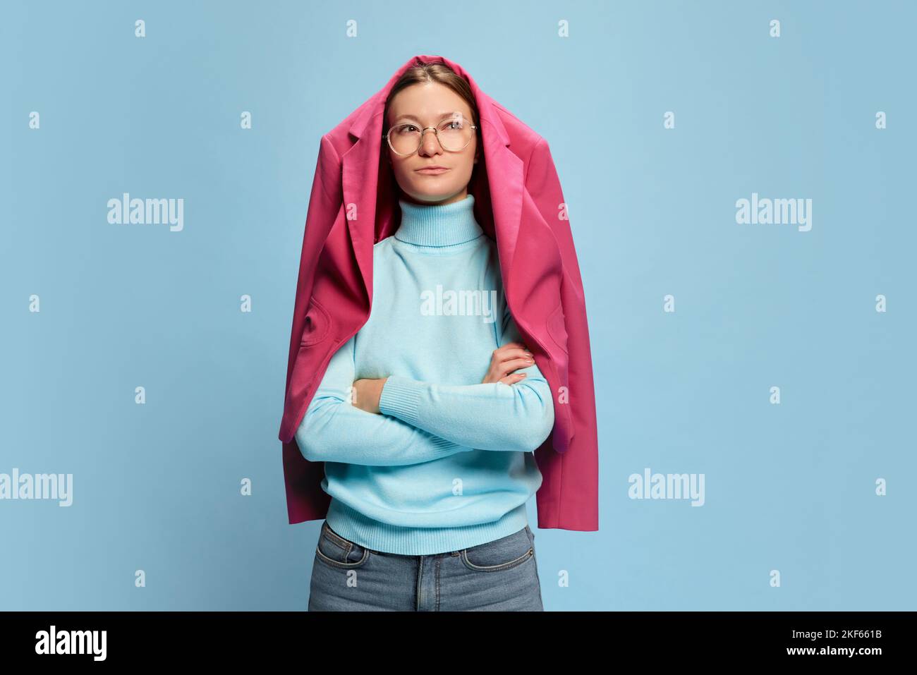 Portrait of young woman posing in trendy glasses and vivid pink jacket ...