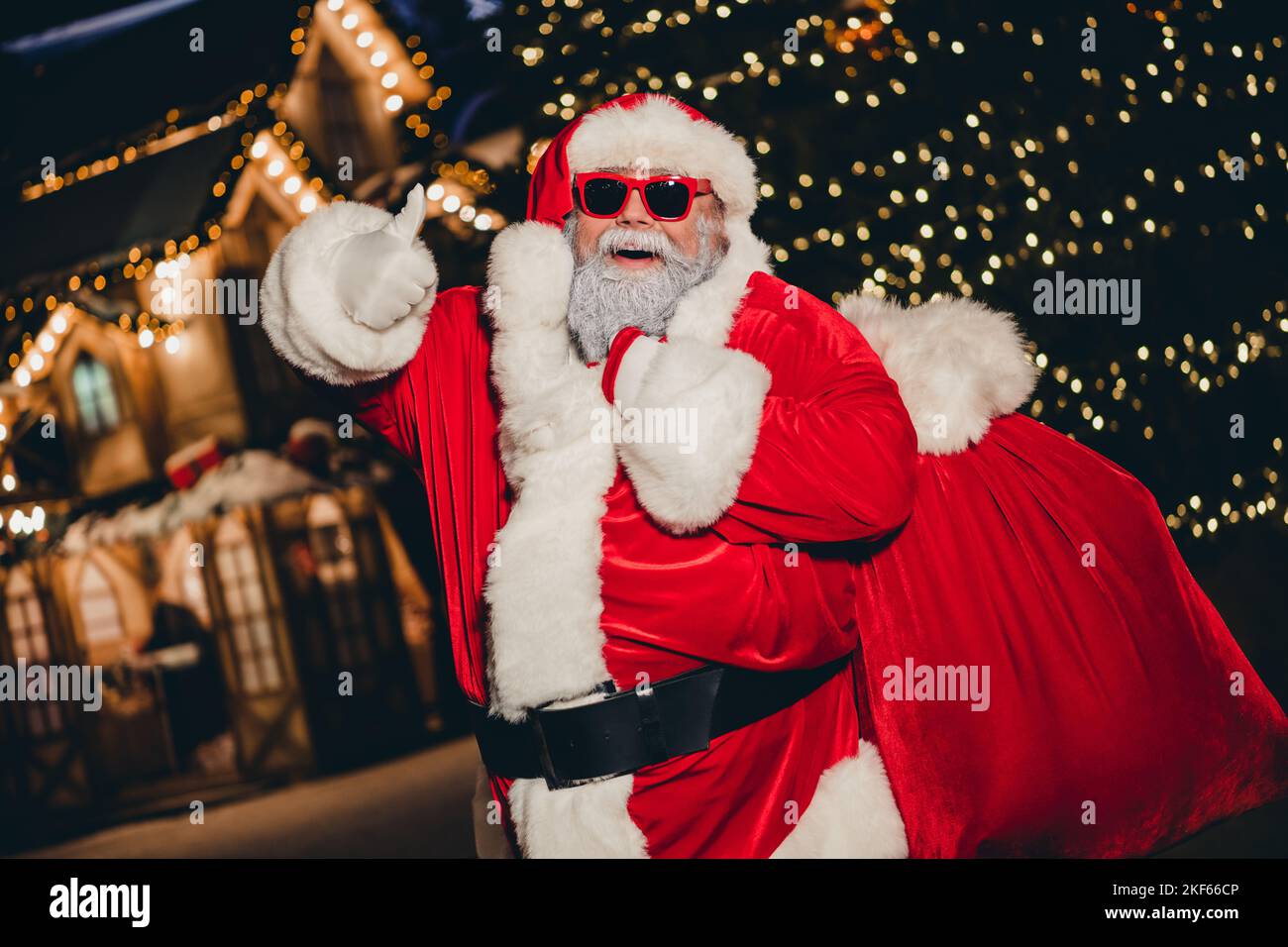 Photo of funky aged man santa costume hold gifts sack demonstrate thumb ...