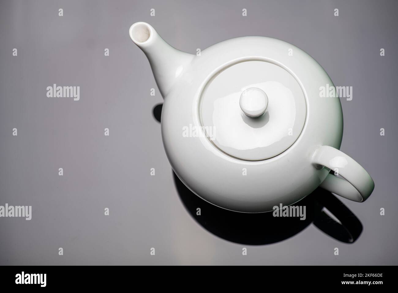 a white teapot on a acrylic background with black shadow, isolated ...