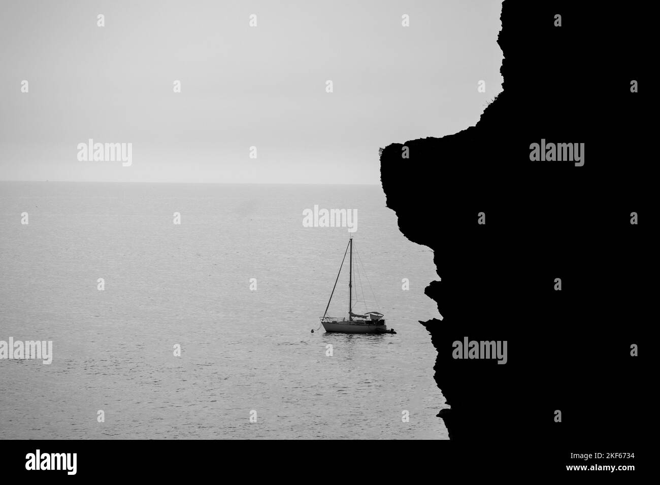 A grayscale shot of a silhouette of a cliff with a background of a ...