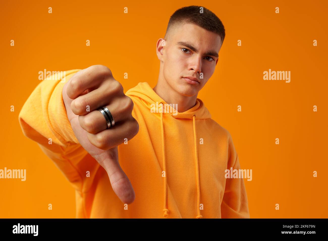 Young man showing a sign of dislike against yellow background Stock ...