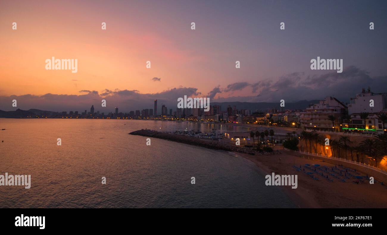A view of the coastline with buildings under the purple shaded sunset ...