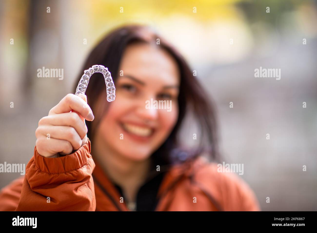 Happy young woman smiling with invisible teeth aligner during fall ...