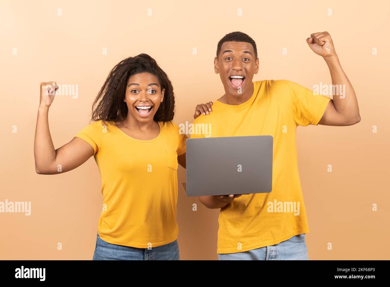 Big win concept. Overjoyed black couple holding laptop, cheering ...