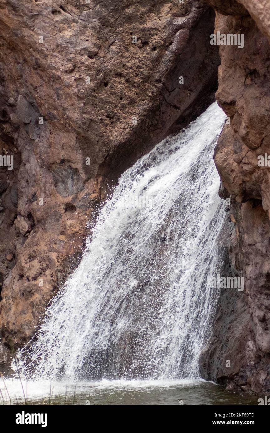 The vertical shot of a waterfall flowing down the rocky slope Stock ...